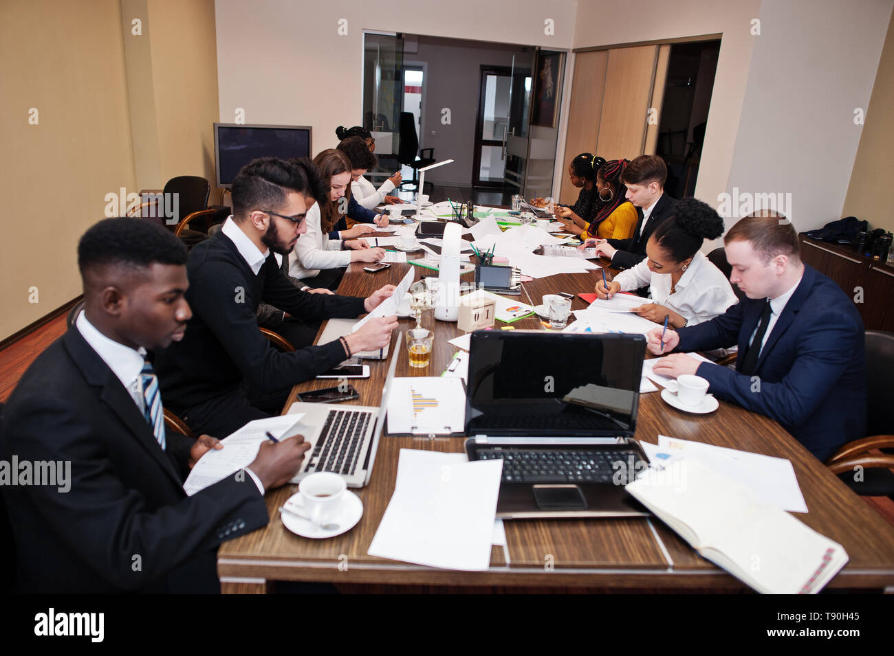 Multiracial business team addressing meeting around boardroom table ...