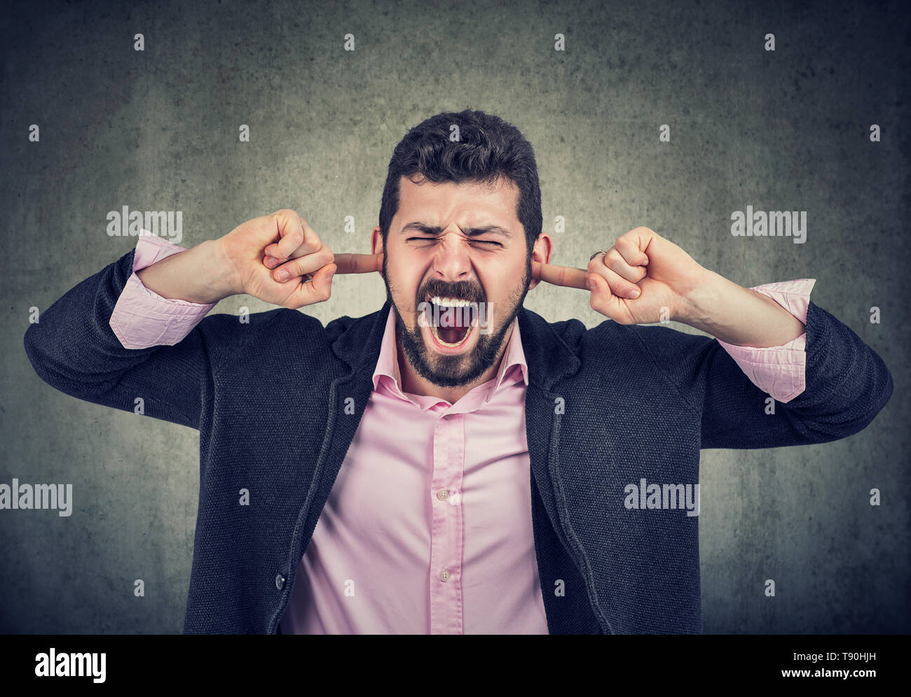 Frustrated man plugging his ears with fingers feeling angry Stock Photo ...