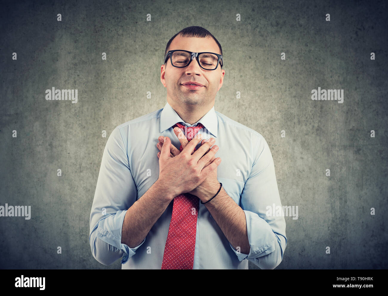 Business man with eyes closed keeps hands on chest near heart, shows ...