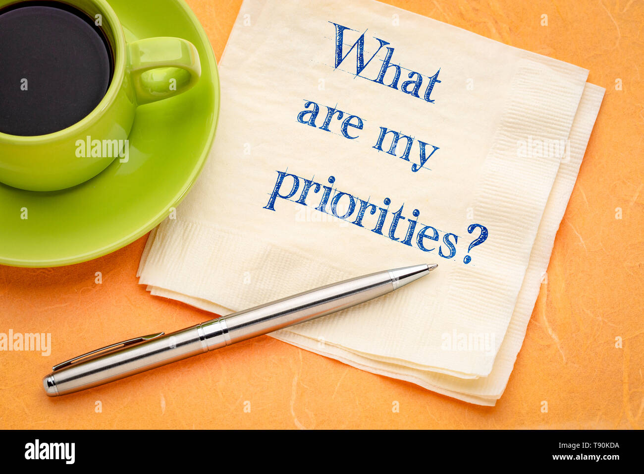 What are my priorities? A handwritten question on a napkin with a cup ...
