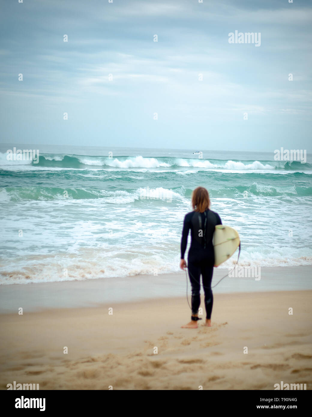 Surfer feeling the sea by the sand, looking at the waves from the beach ...
