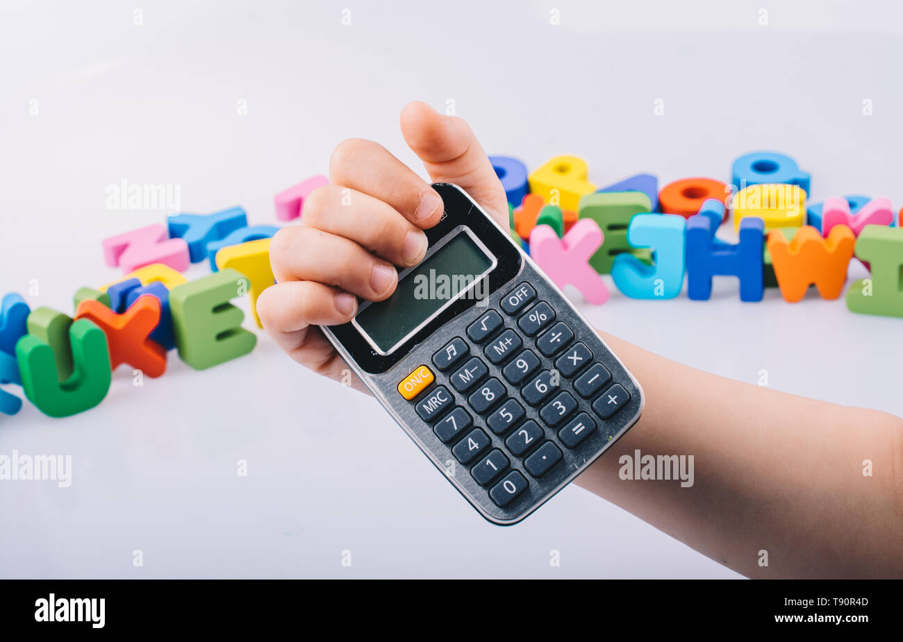 Little calculator in hand with colorful letters behind on white Stock ...