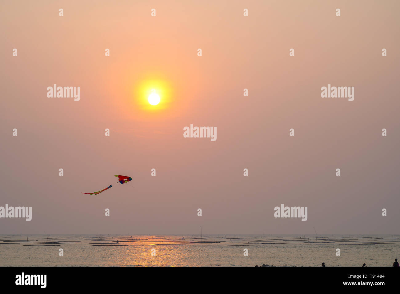 View from the beach with a yellow glowing sun setting in the horizon ...