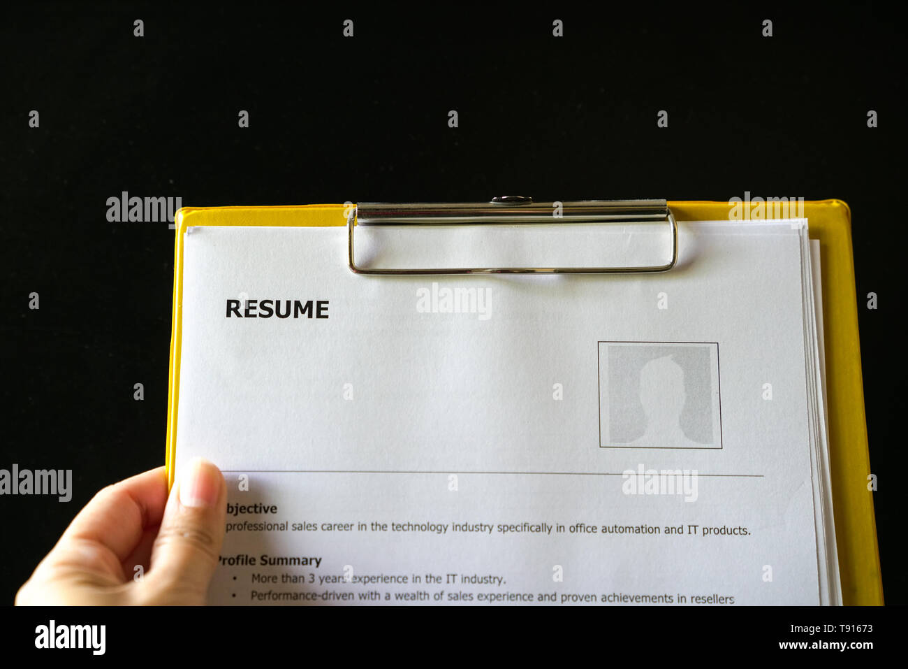 Resume on a clipboard with office table background. A hiring or ...