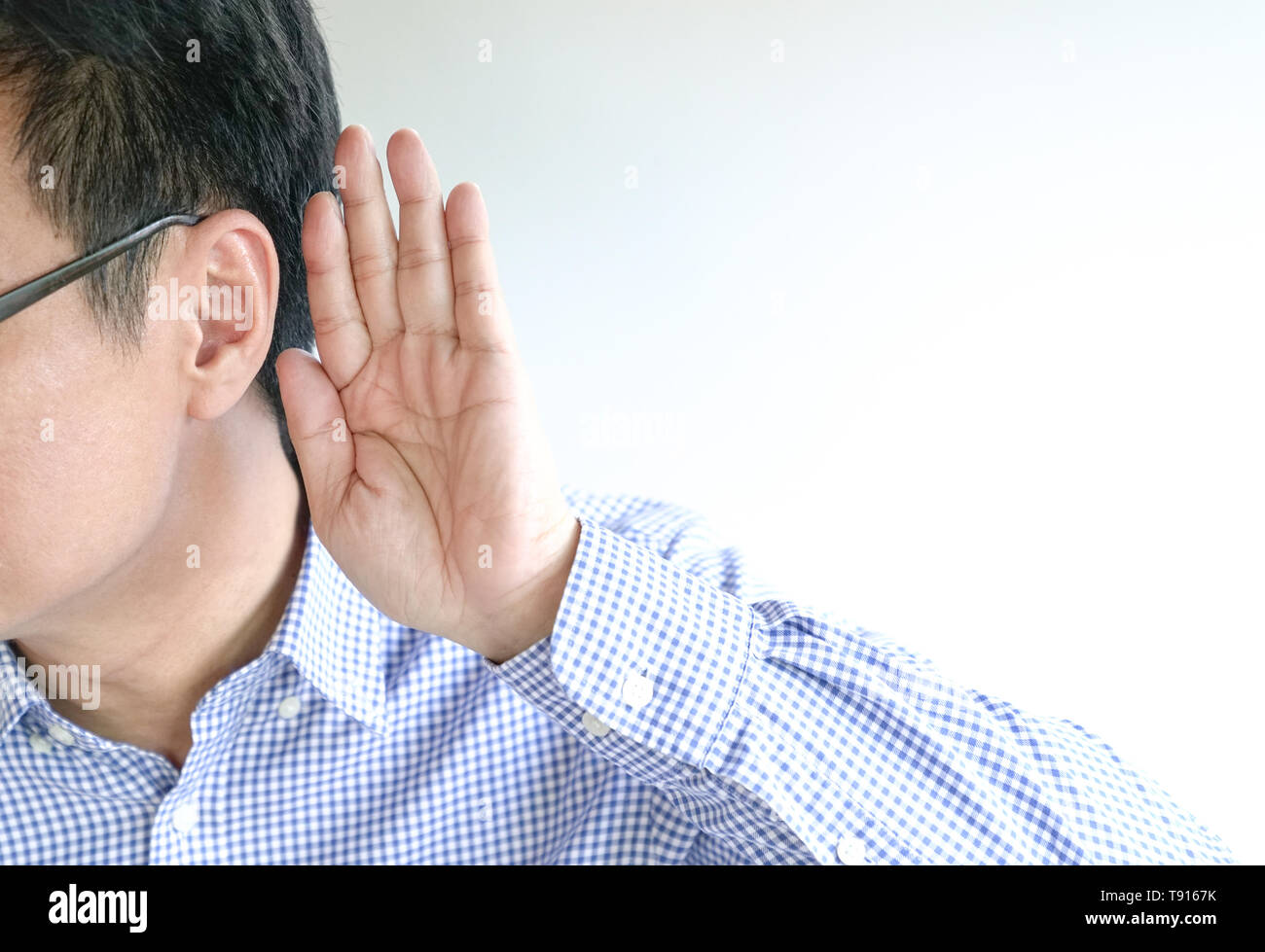 Businessman has his hand next to his ear, a listening gesture or ...