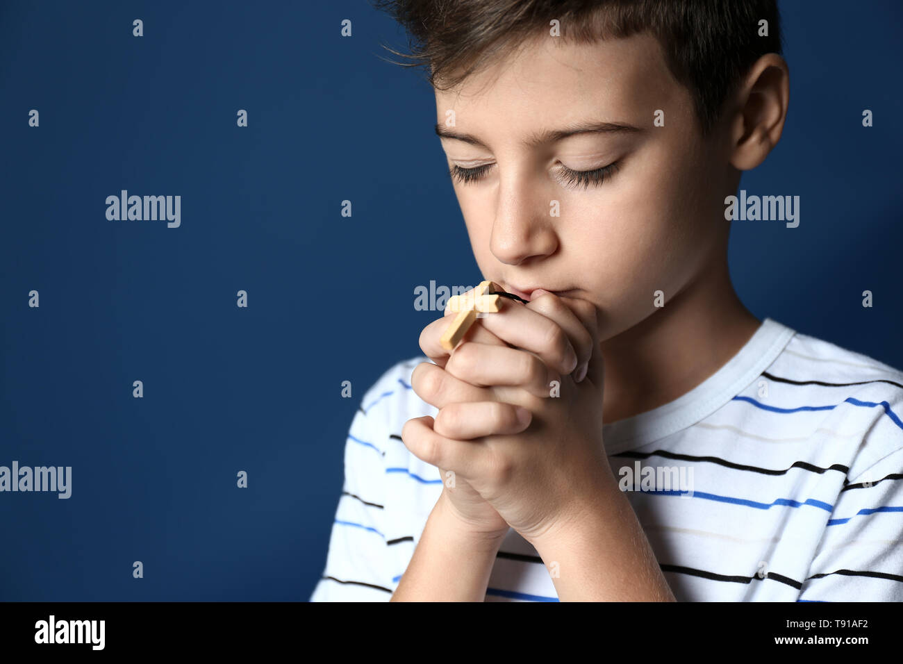 Little boy with cross praying on color background Stock Photo - Alamy