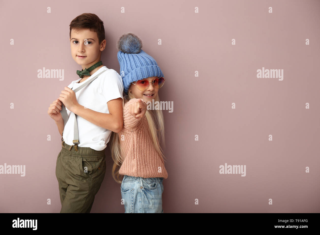 Cute boy and girl in fashionable clothes on color background Stock ...