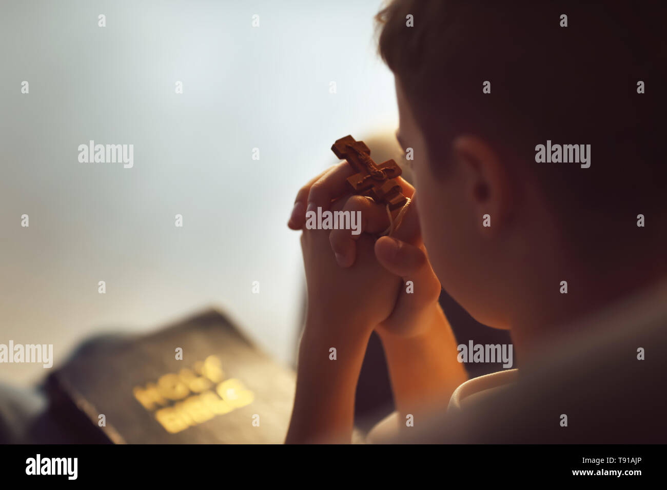 Little boy with cross praying at home Stock Photo - Alamy