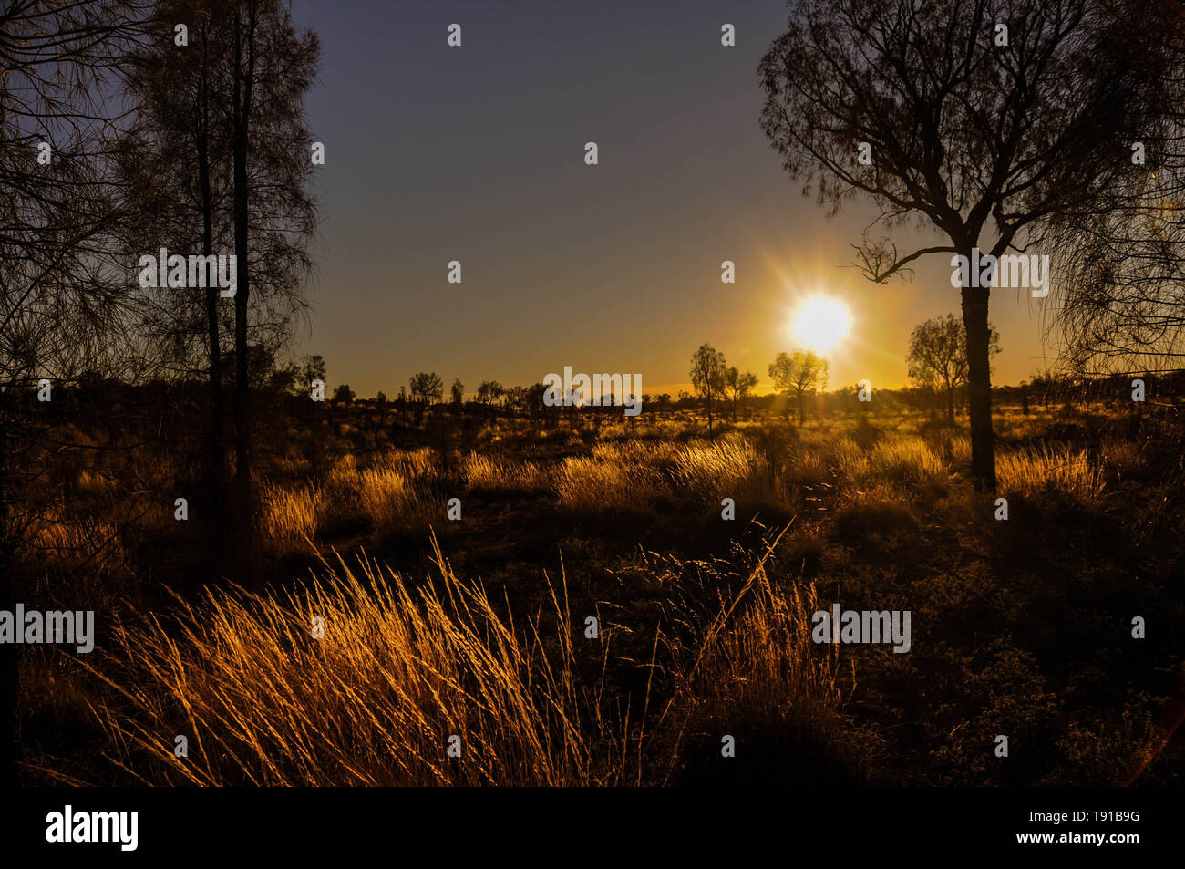The sun sets over a lonely Australian desert outside a campsite bathing ...