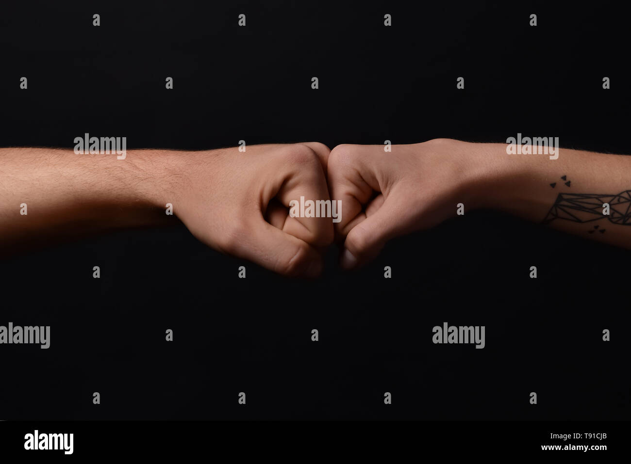 Man and woman making fist bump gesture on dark background Stock Photo ...