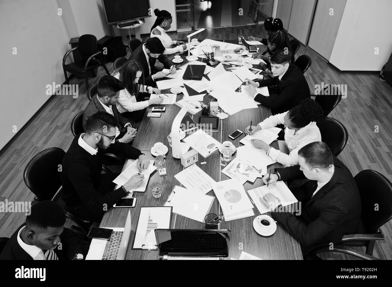 Multiracial business team addressing meeting around boardroom table ...