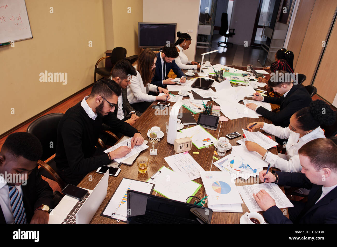 Multiracial business team addressing meeting around boardroom table ...
