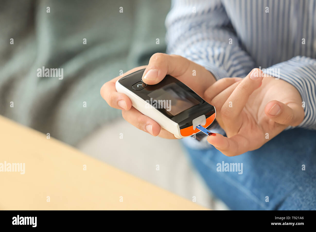 Diabetic woman taking blood sample with digital glucometer at home ...