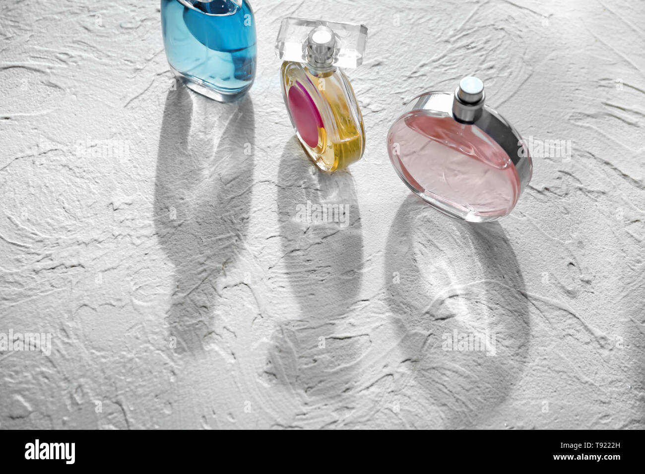Different bottles of perfume on white textured background Stock Photo ...