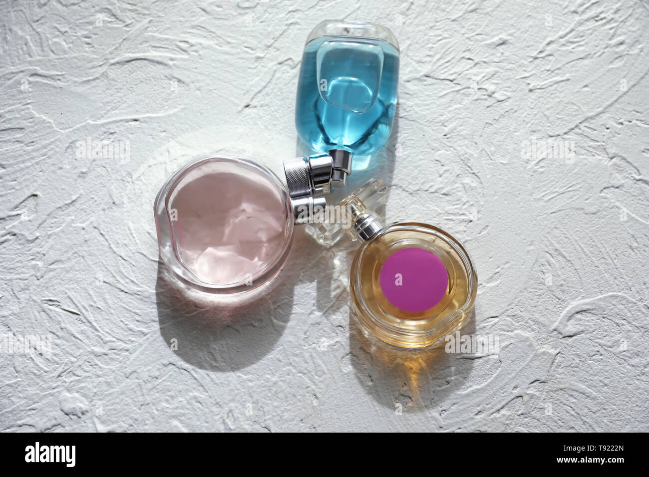 Different bottles of perfume on white textured background Stock Photo ...