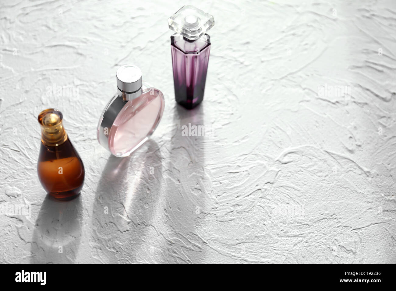 Different bottles of perfume on white textured background Stock Photo ...