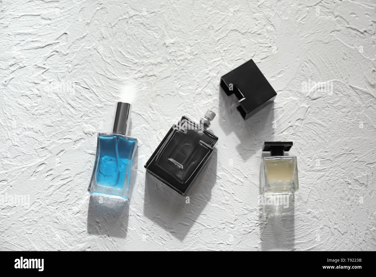 Different bottles of perfume on white textured background Stock Photo ...