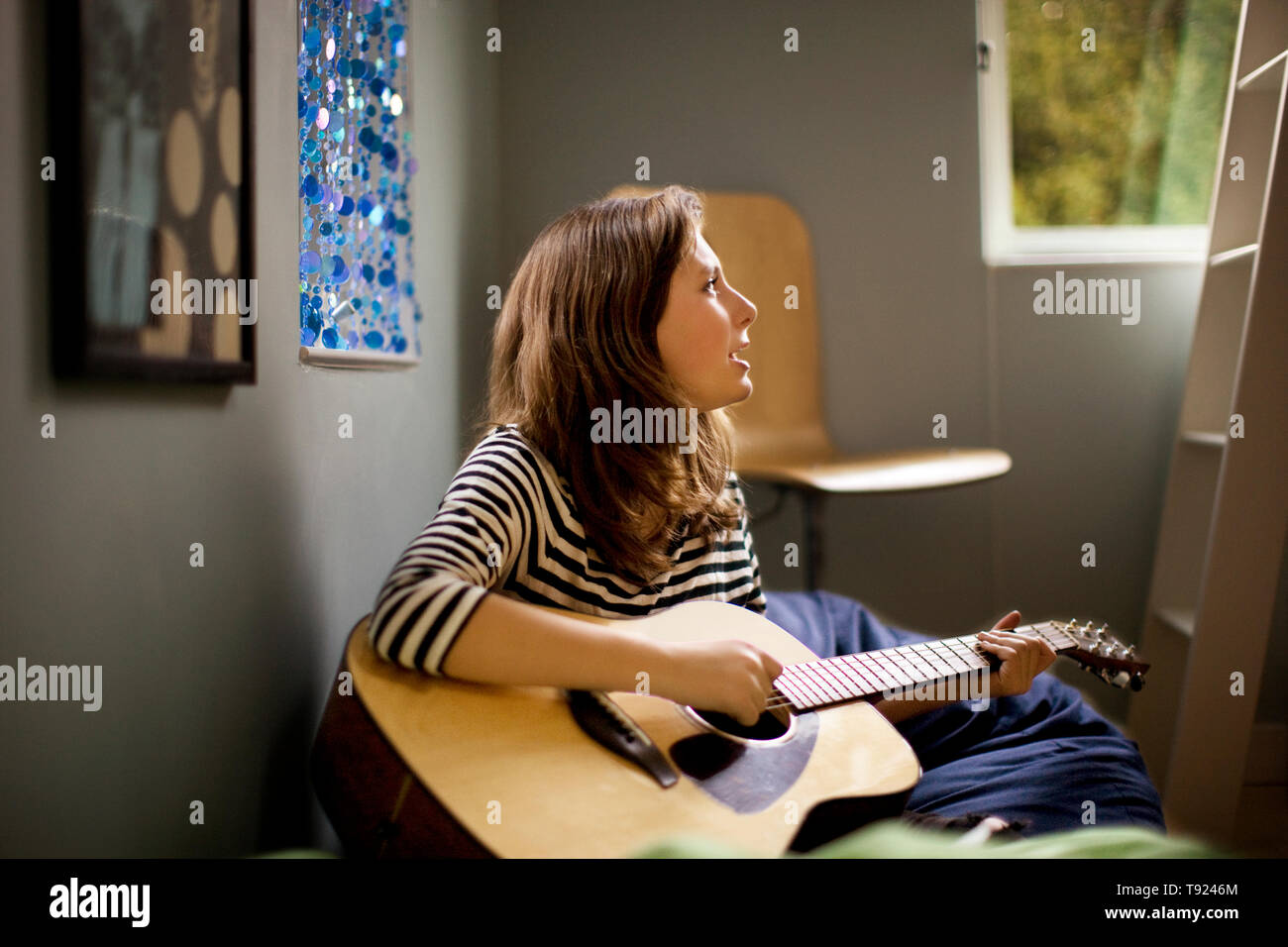 Teenage girl playing her guitar and singing Stock Photo - Alamy