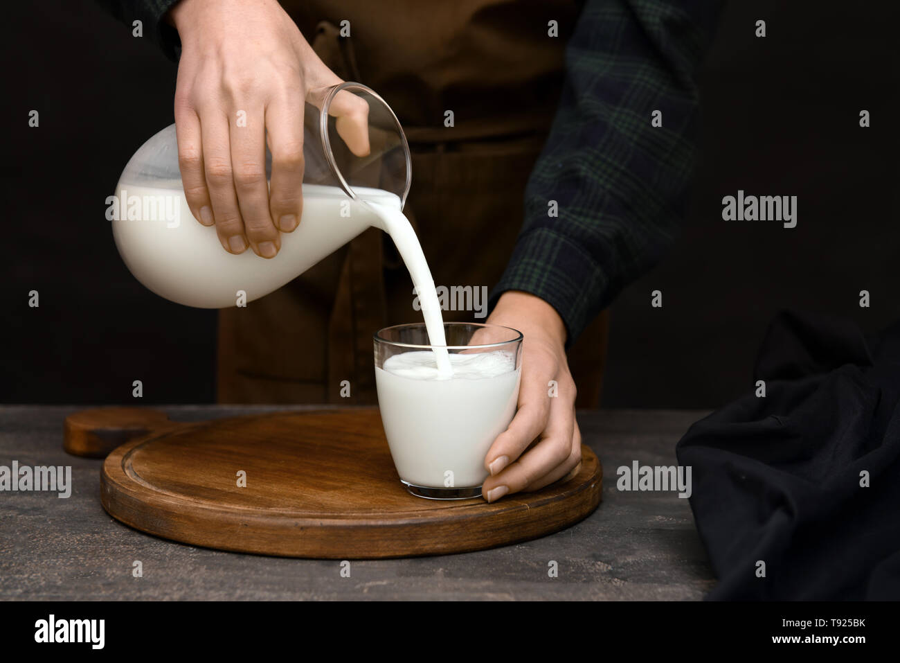 Woman pouring fresh milk from jug into glass on table Stock Photo - Alamy