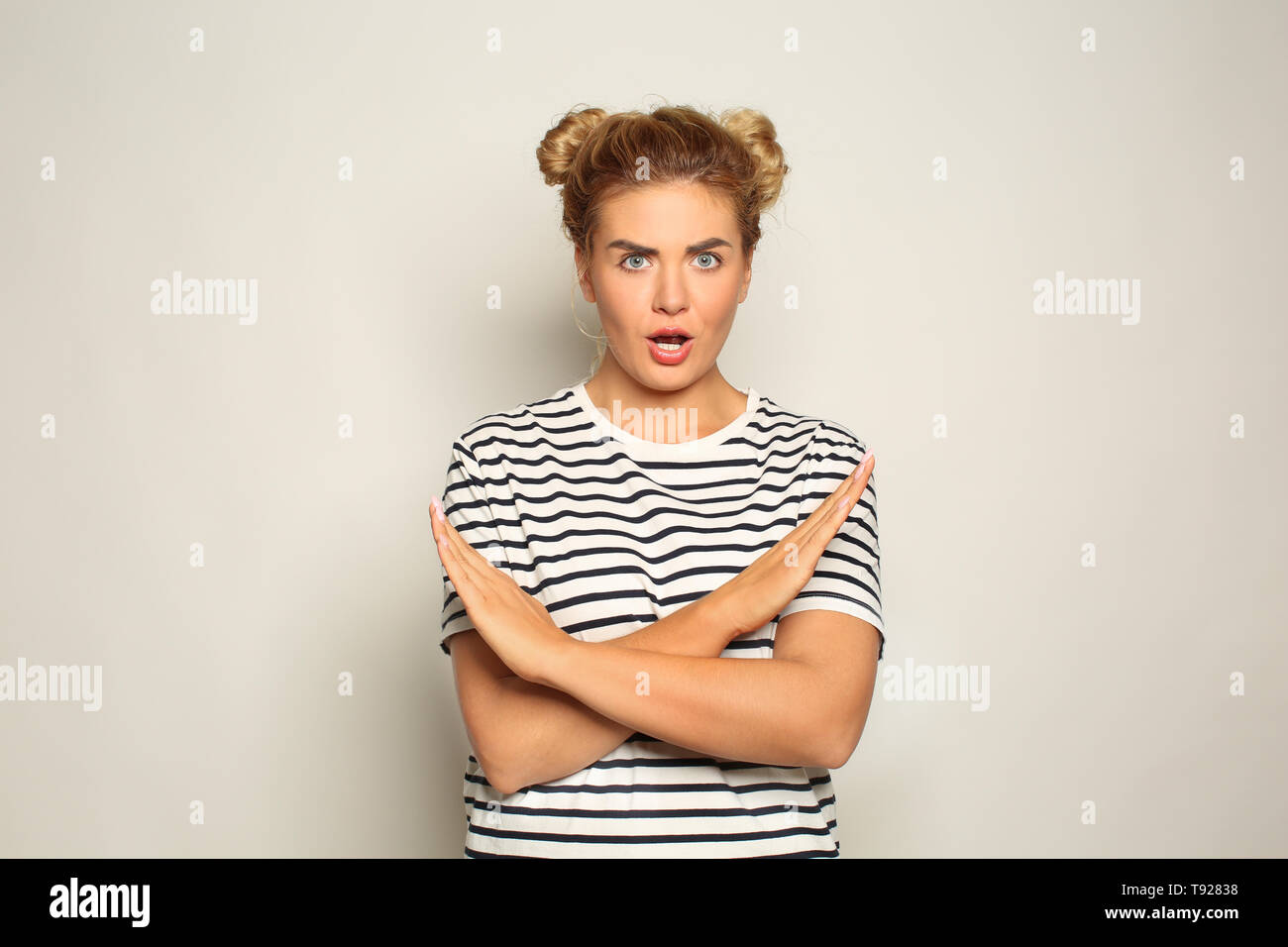Portrait of beautiful young woman rejecting something on light ...
