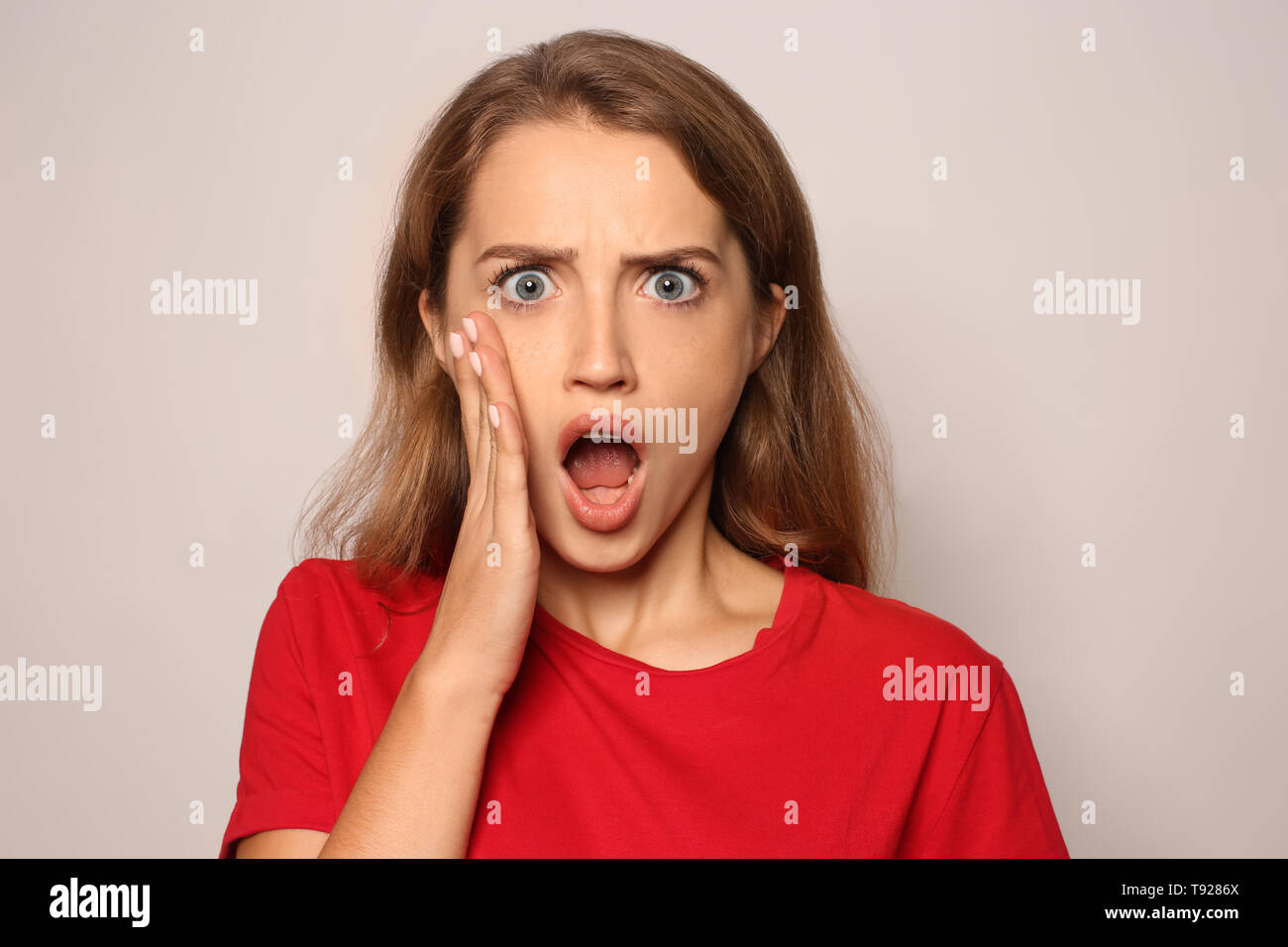 Portrait of shocked young woman on light background Stock Photo - Alamy