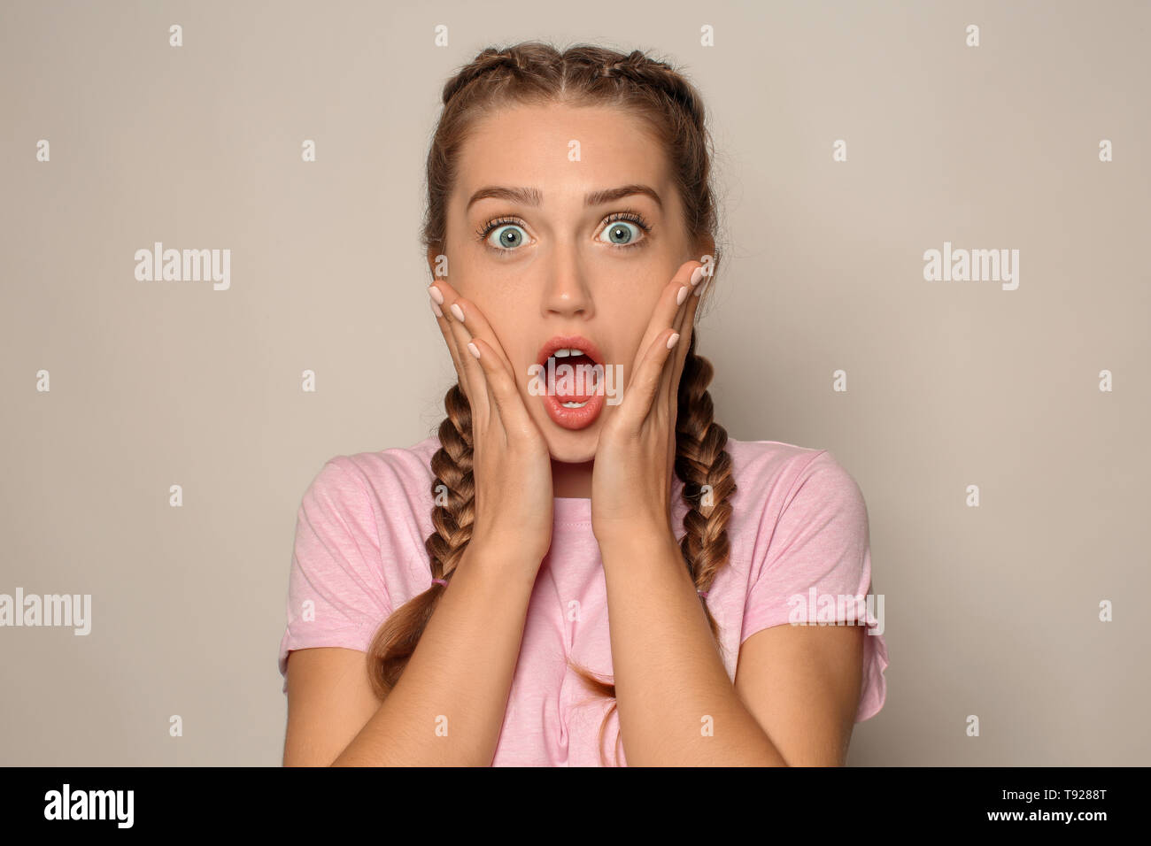 Portrait of shocked young woman on light background Stock Photo - Alamy