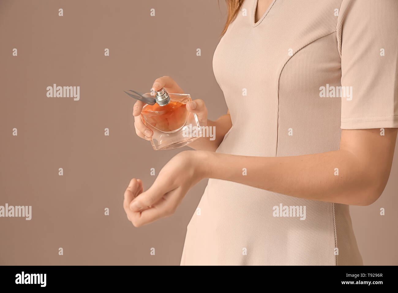 Woman applying perfume against color background Stock Photo - Alamy