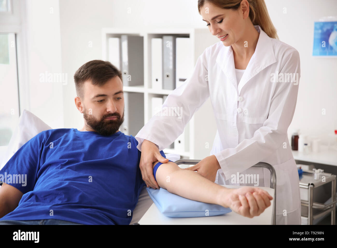 Female doctor preparing male donor for blood transfusion in hospital ...