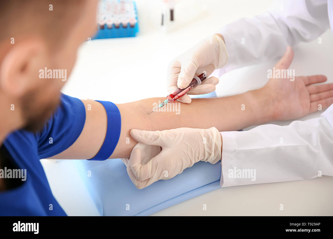 Female doctor drawing a blood sample of male patient in clinic Stock ...