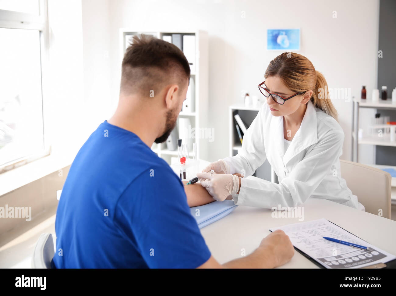 Female doctor drawing a blood sample of male patient in clinic Stock ...