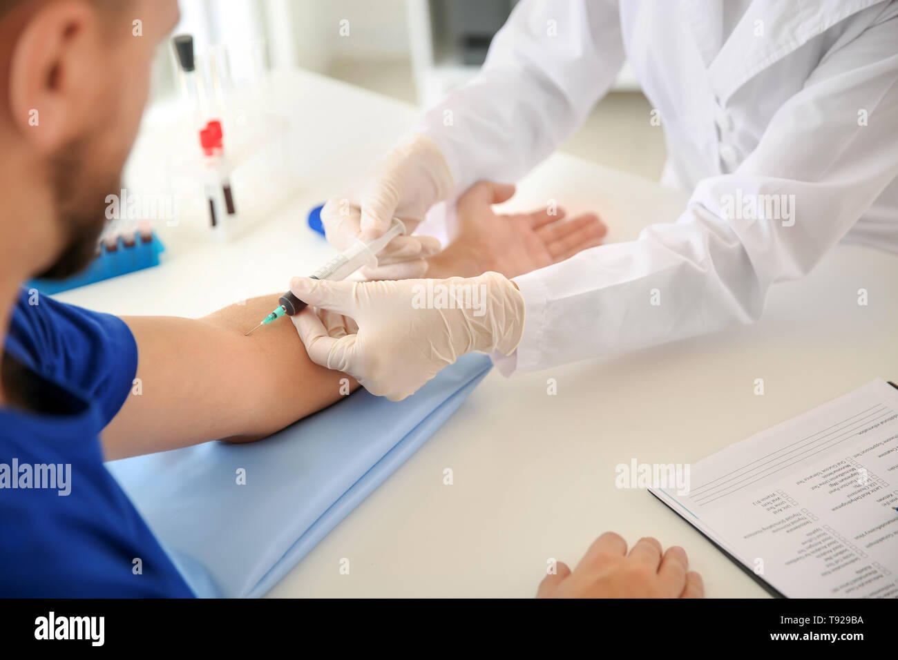Female doctor drawing a blood sample of male patient in clinic Stock ...