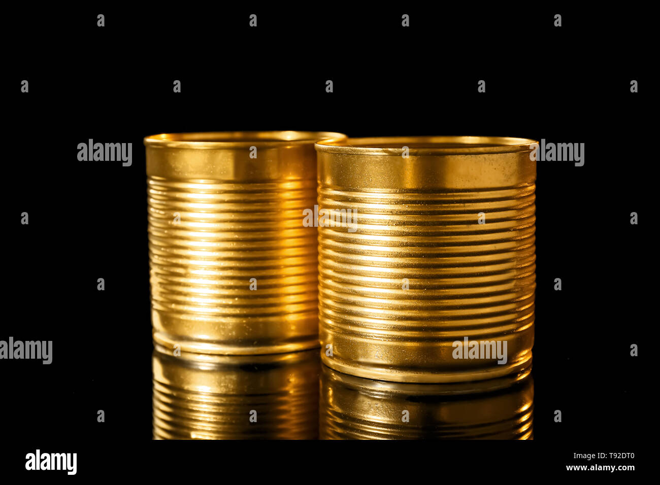 Golden tin cans on black background Stock Photo - Alamy
