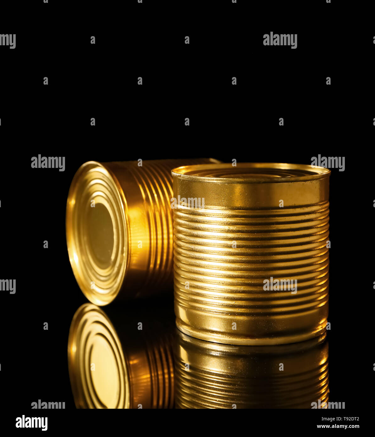 Golden tin cans on black background Stock Photo - Alamy