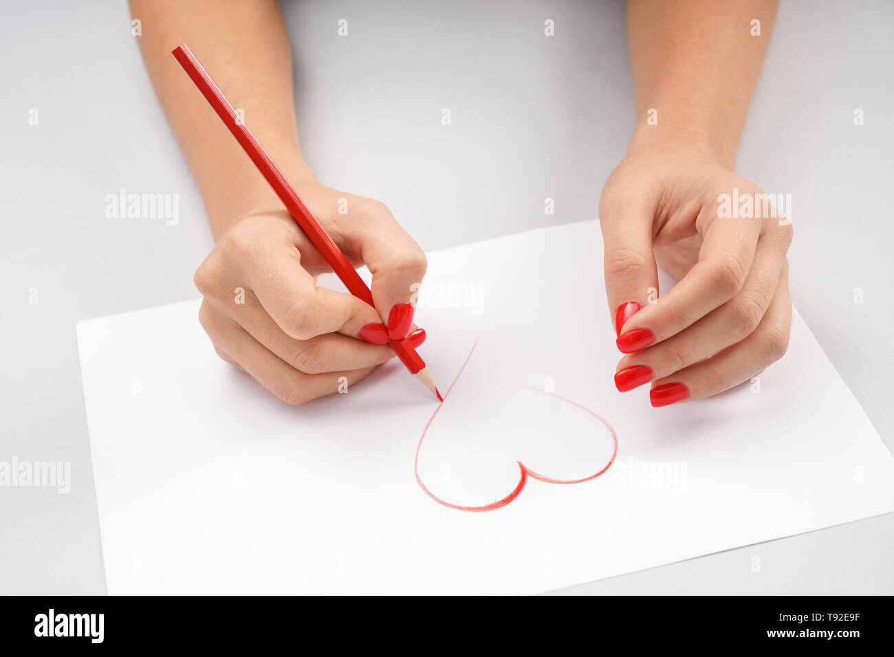 Woman drawing heart on sheet of paper Stock Photo - Alamy