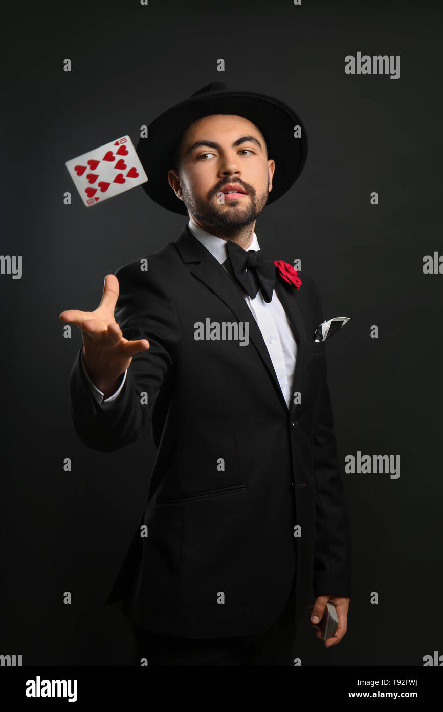 Male magician showing tricks with card on dark background Stock Photo ...