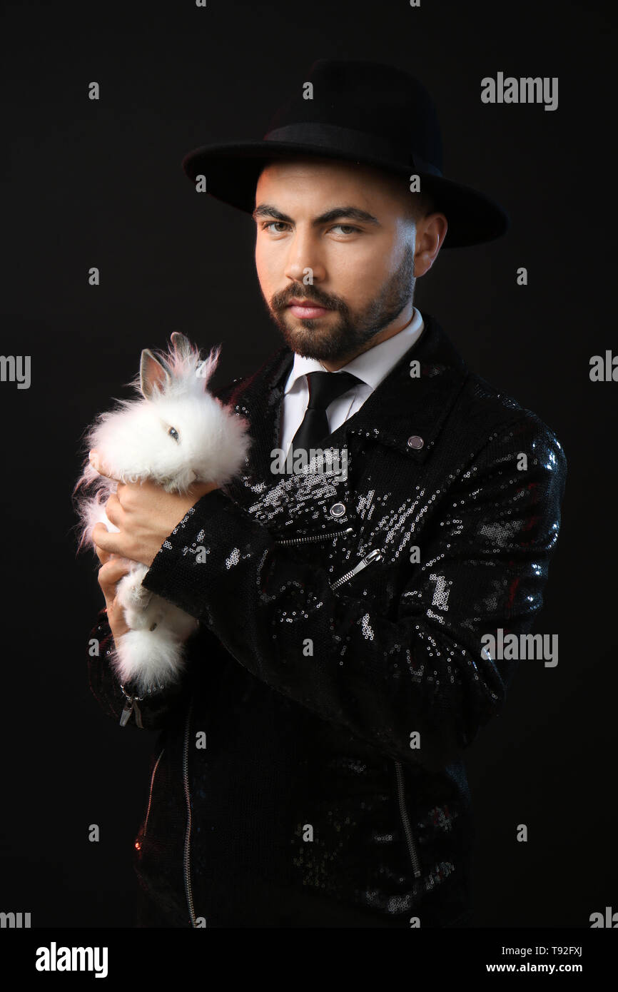 Male magician with white rabbit on dark background Stock Photo - Alamy