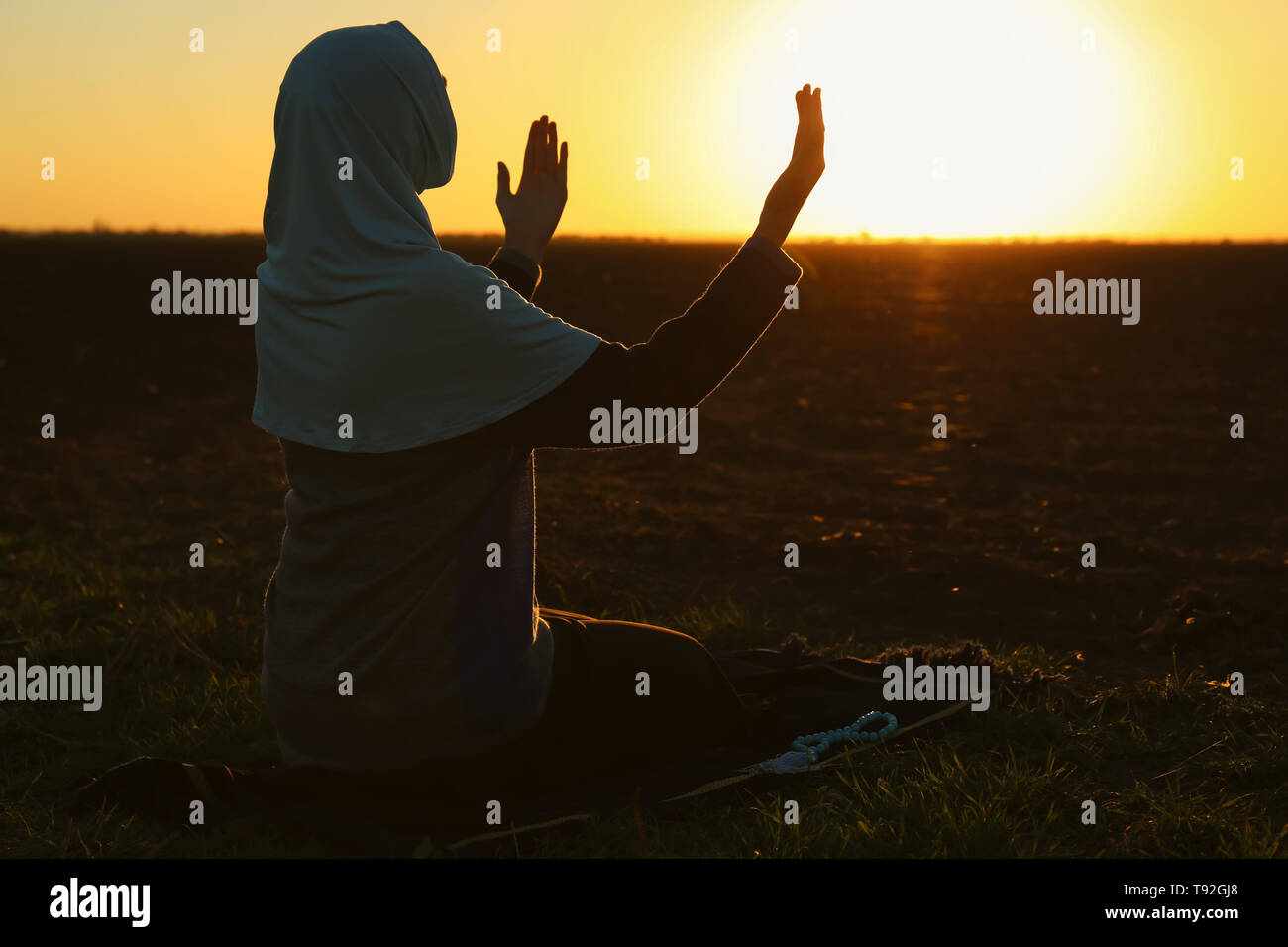 Young Muslim woman praying outdoors at sunrise Stock Photo - Alamy