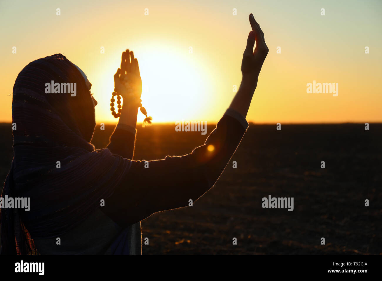 Young Muslim woman praying outdoors at sunrise Stock Photo - Alamy