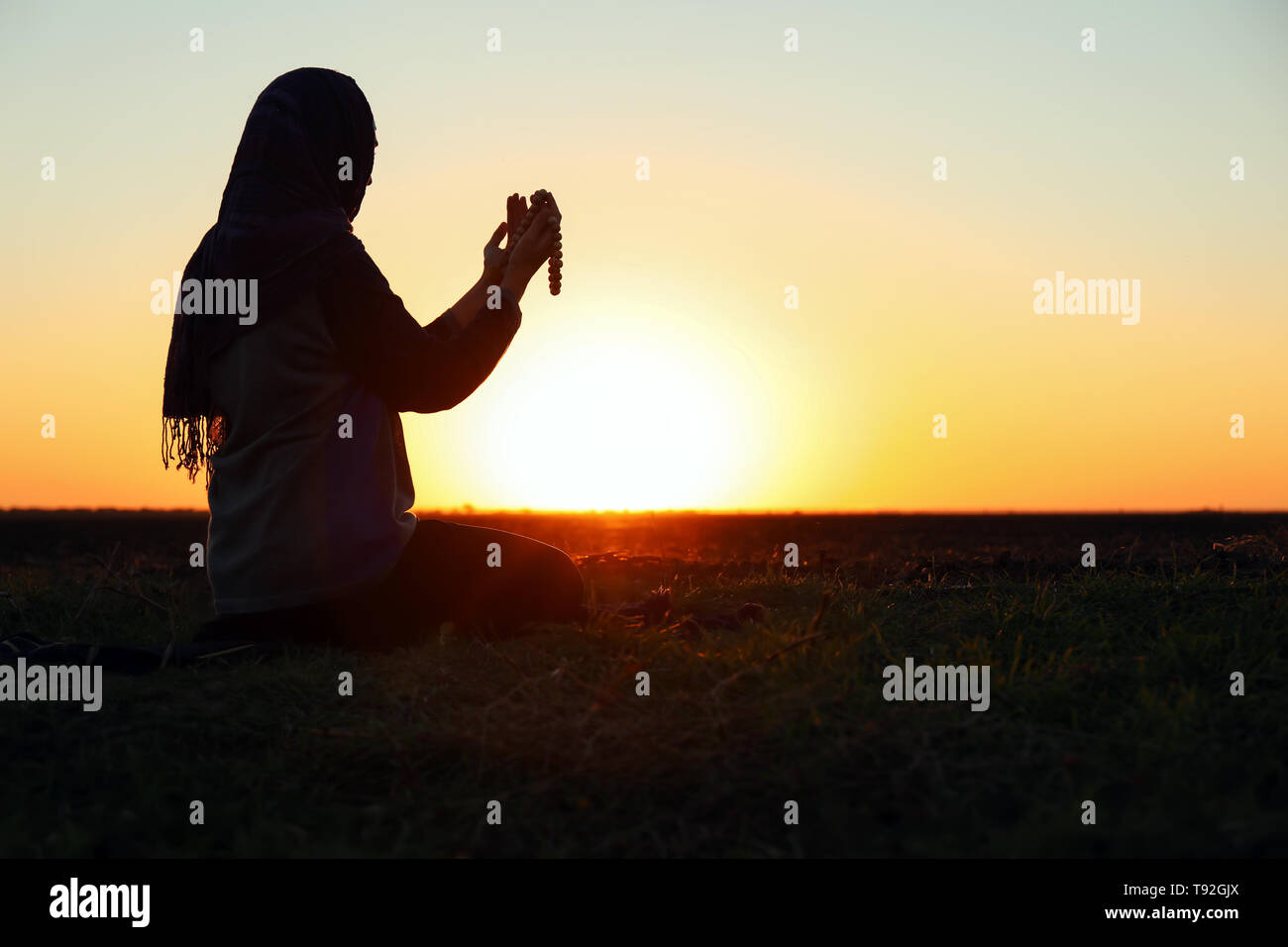 Young Muslim woman praying outdoors at sunrise Stock Photo - Alamy