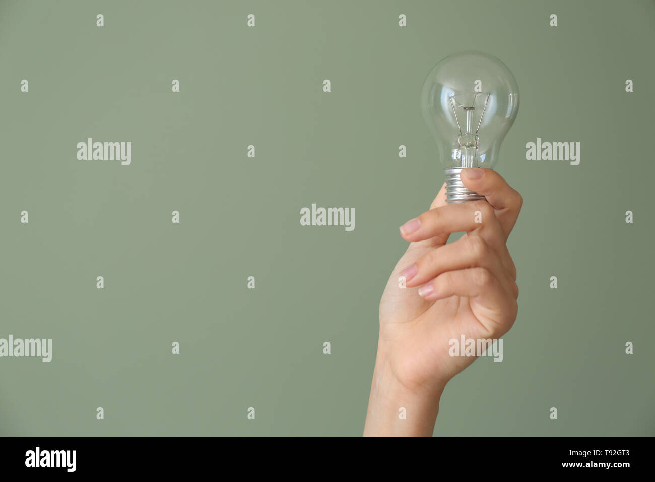 Female hand with eco light bulb on color background Stock Photo - Alamy