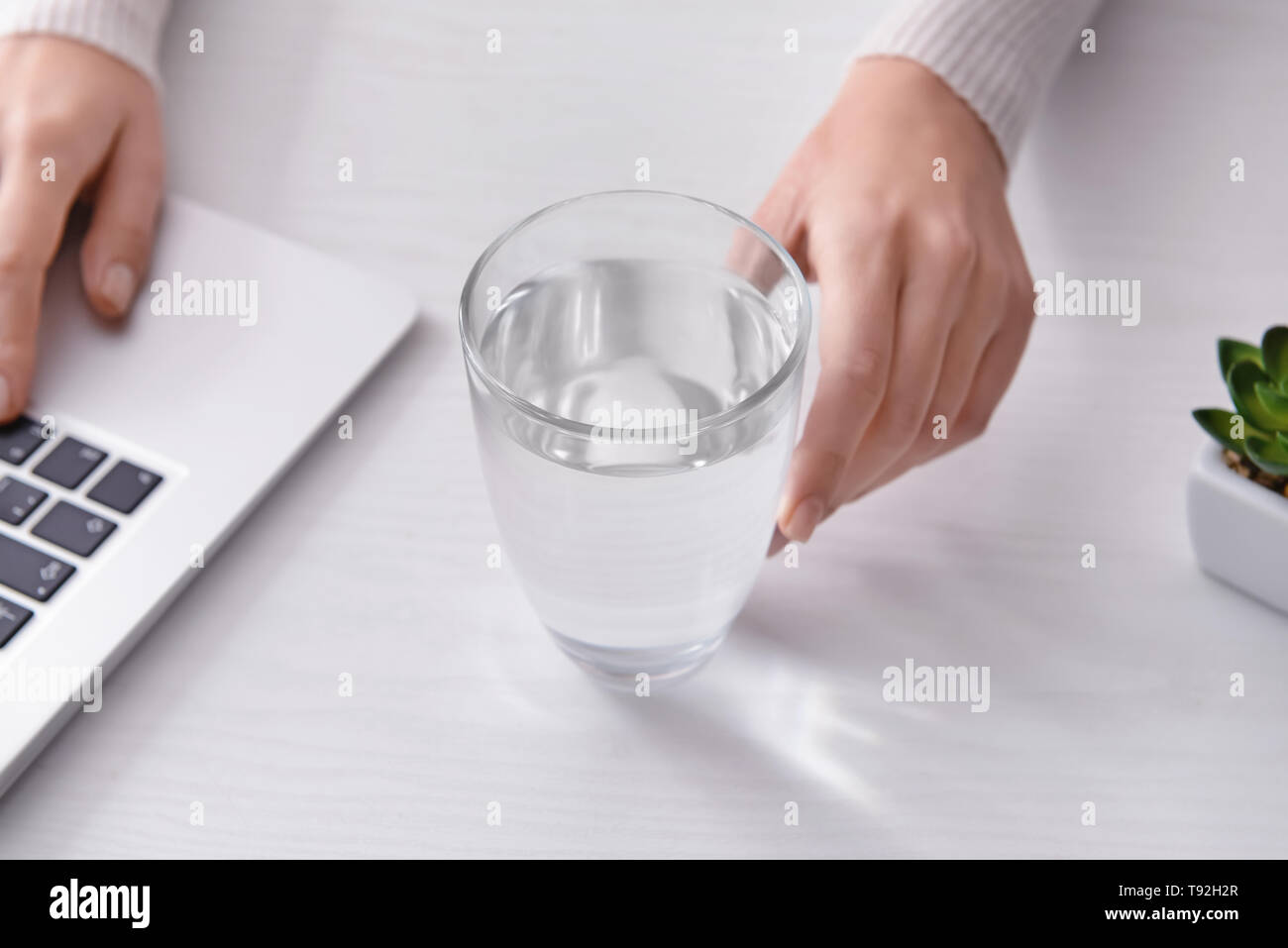 Woman drinking fresh water while working on laptop Stock Photo - Alamy
