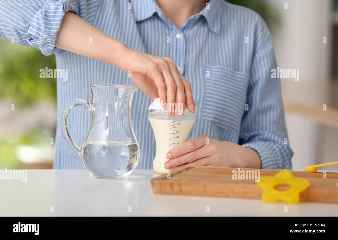 Woman preparing baby formula at table Stock Photo - Alamy