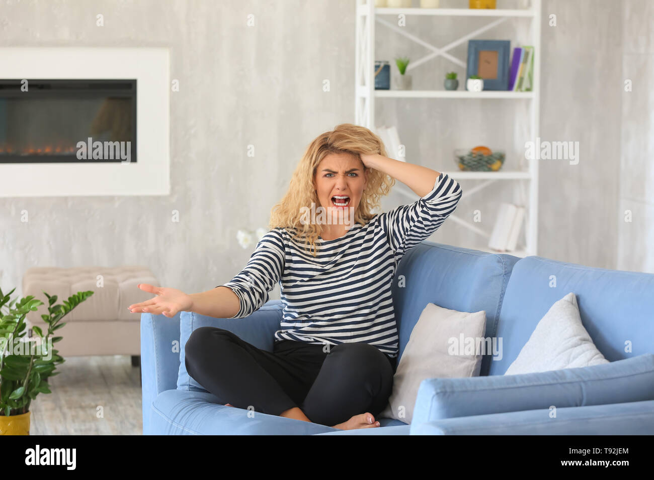 Angry young woman sitting on sofa at home Stock Photo - Alamy