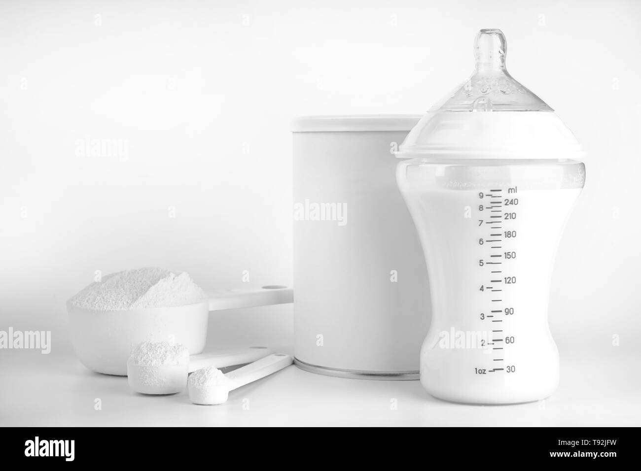 Bottle of milk for baby and measuring scoops with powder on light ...