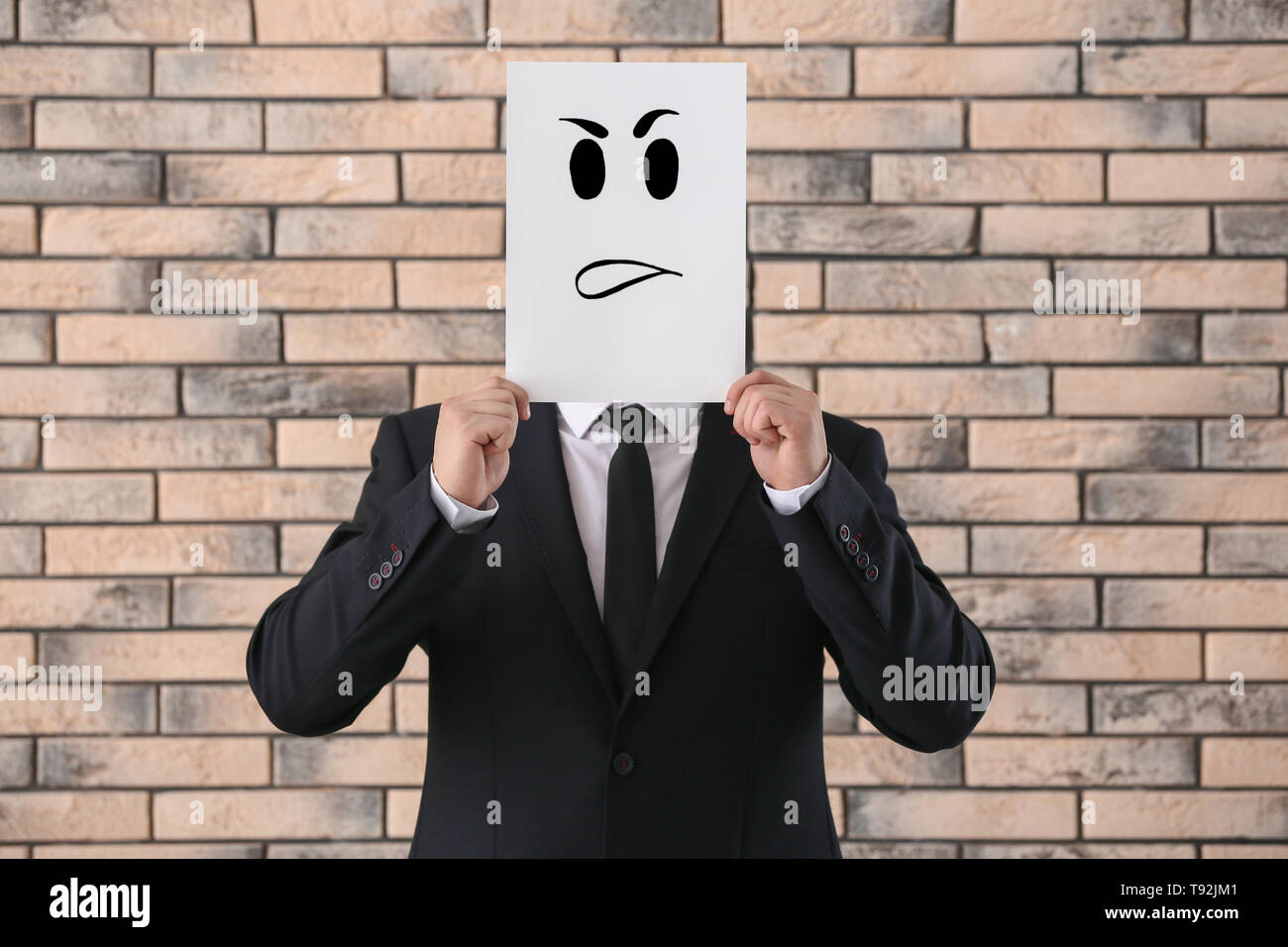 Businessman hiding face behind sheet of paper with drawn emoticon ...