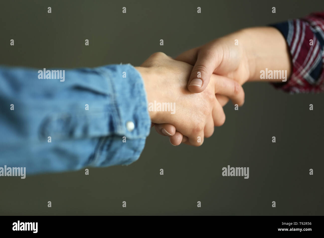 People shaking hands on grey background Stock Photo - Alamy