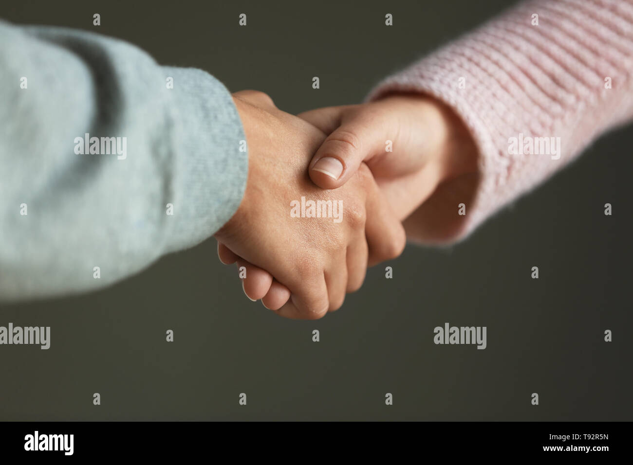 People shaking hands on grey background Stock Photo - Alamy