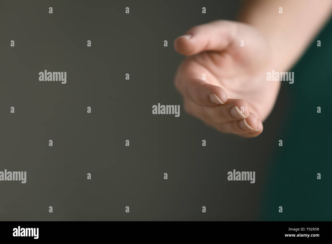 Woman reaching out for handshake on grey background Stock Photo - Alamy