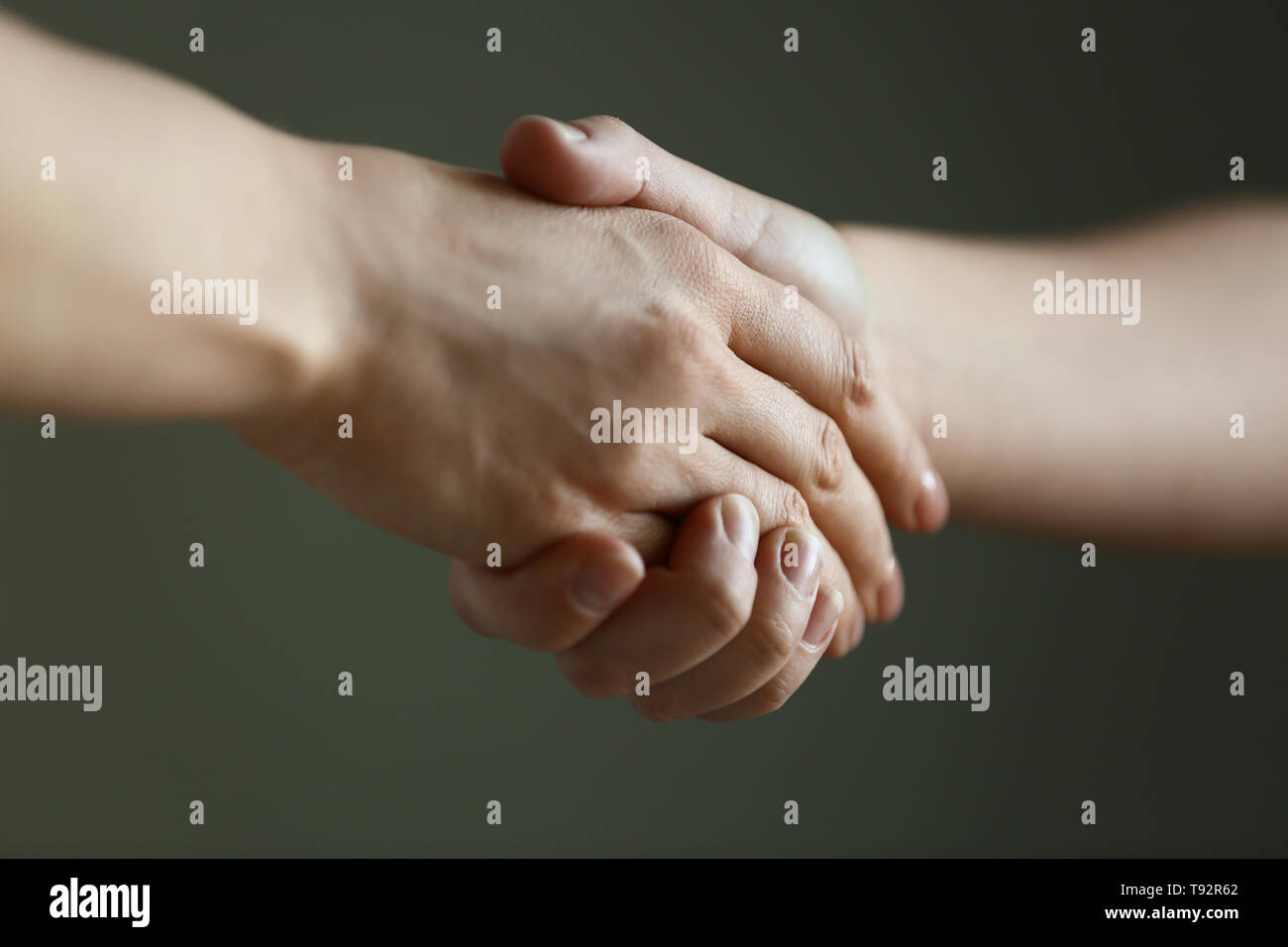 People shaking hands on grey background Stock Photo - Alamy