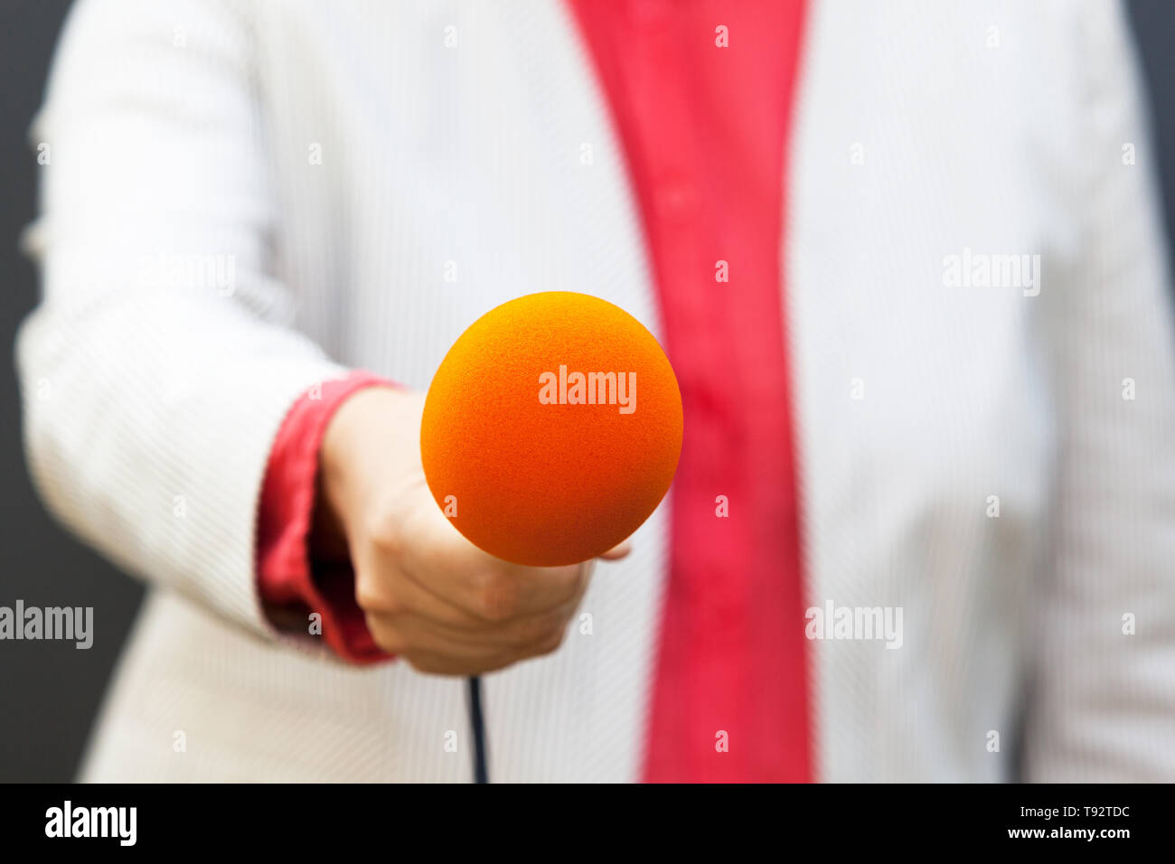 Female reporter holding microphone, making interview Stock Photo - Alamy